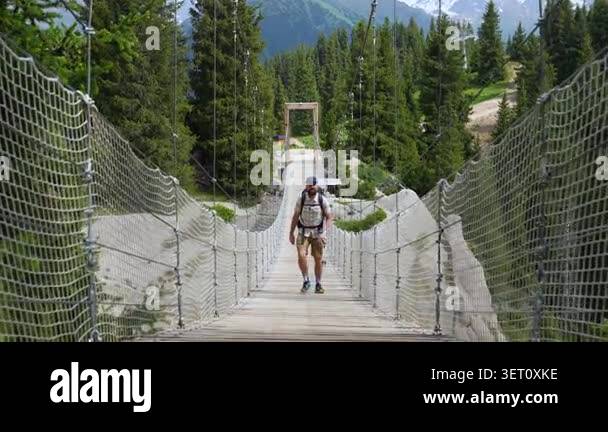 A lone hiker with a backpack confidently walks across a long, airy ...