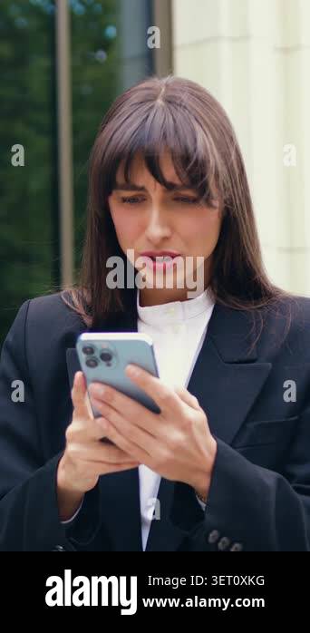 Distressed businesswoman looking at her phone with shock and concern ...