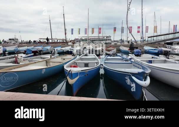 Bardolino, Italy - May 14, 2026 - Boats docked in a harbor with flags ...