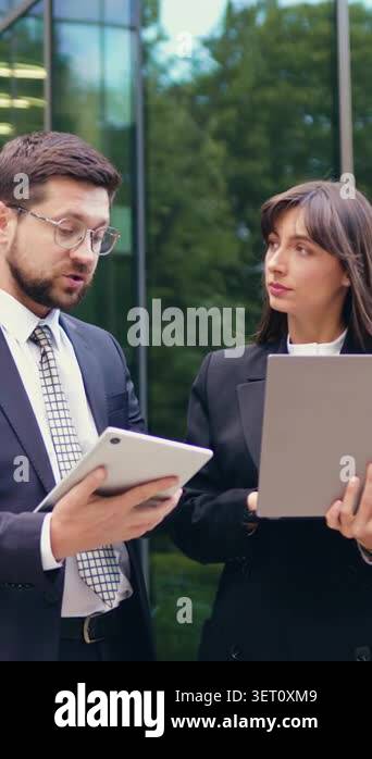 Two business colleagues, man and woman, talking and working on a laptop ...