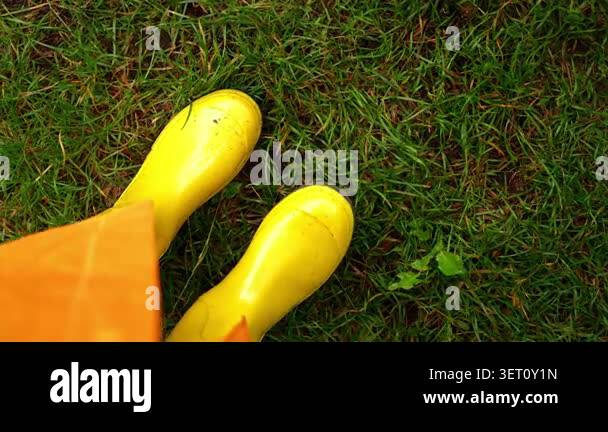 Yellow rubber boots standing on wet road under rainfall in city ...