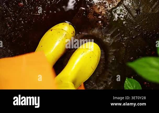 Yellow rubber boots standing on wet road under rainfall in city ...