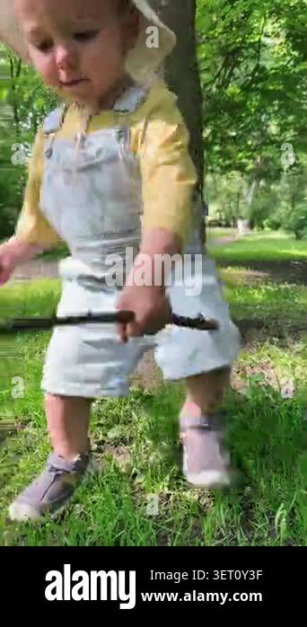 Toddler playing with a stick in a green park close up Stock Video ...