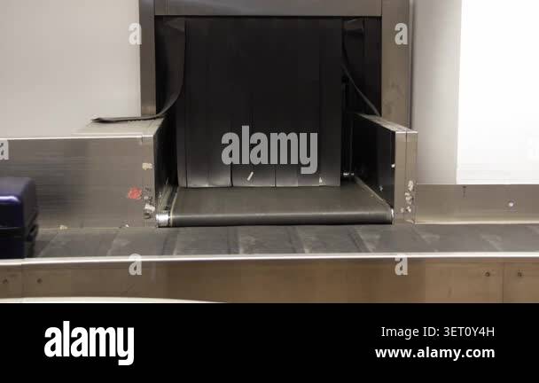 Luggage moving on a conveyor belt towards a security scanner at an ...