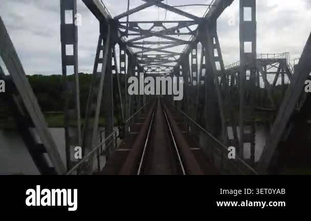 POV shot from a train crossing a metal bridge over a river, then ...