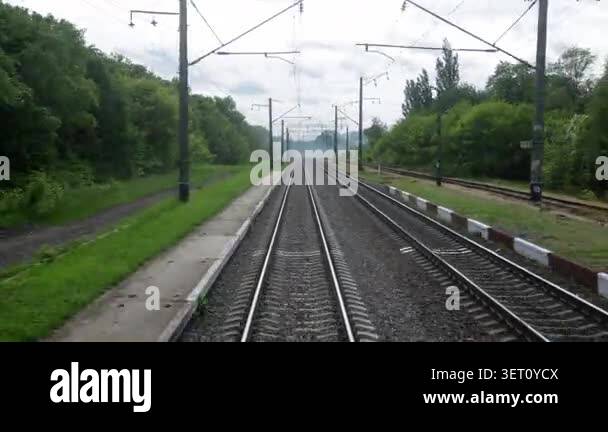 POV from a moving train traveling along railway tracks through a lush ...