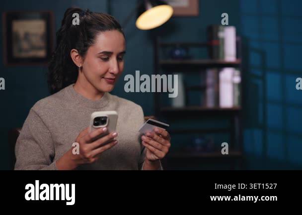 Portrait of positive woman uses banking app on smartphone at home ...