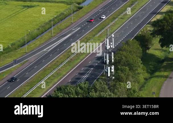 Aerial drone view of a 5G transmission tower beside a highway ...