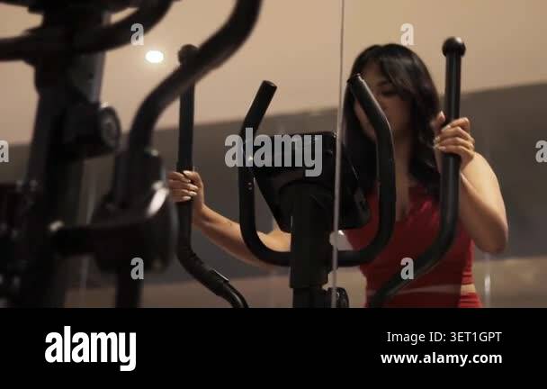 A woman in a red top is actively engaged in a cardio workout on an ...