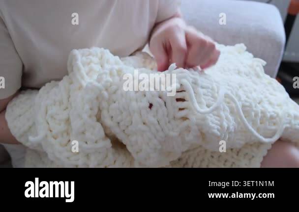 Close up of female hands knitting a cozy, soft white cardigan using ...