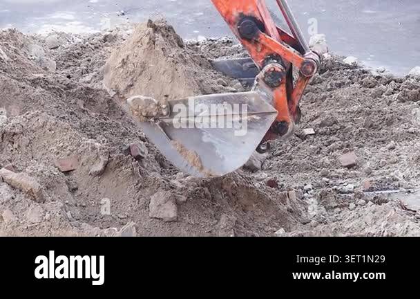 Side view of a hydraulic excavator lifting and moving dirt. Relevant ...