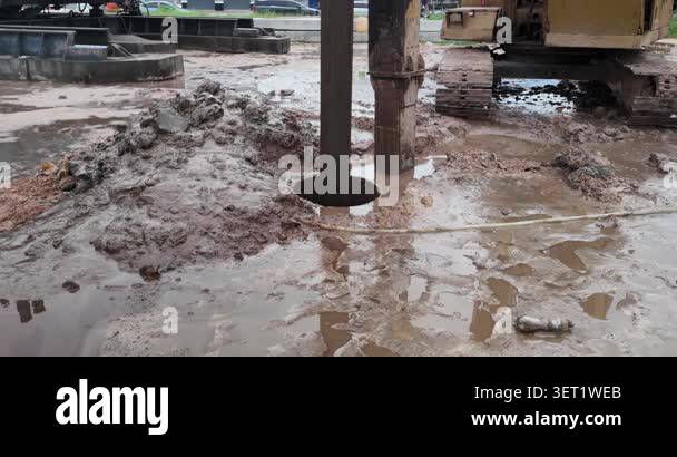 Industrial auger bores into a muddy, waterlogged construction site ...