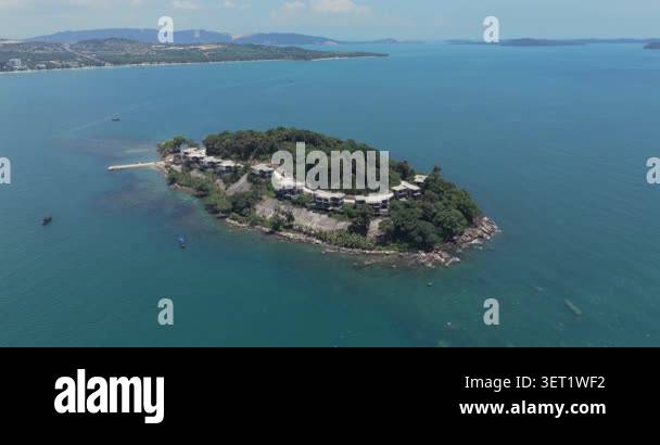 Flyover aerial view of a lush island in a turquoise sea, featuring ...
