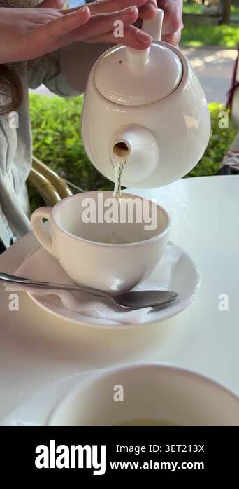 White ceramic teapot and cups on table in nature cafe with soft ...