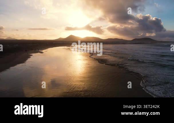 Sunset view at beach features waves rolling in, mountains visible in ...