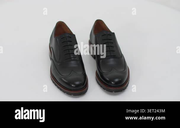 Pair of classic black leather mens brogue shoes with laces rotating on ...