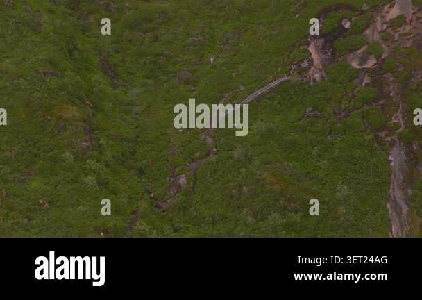 Aerial drone footage of a serpentine mountain road cutting through lush ...