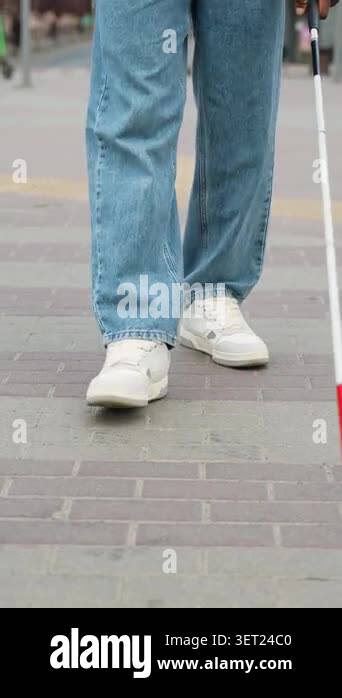 Independent man with sight loss navigating the city sidewalk using a ...