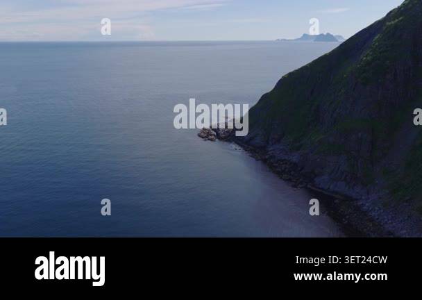 Aerial view of steep green-covered cliffs meeting turquoise sea with ...
