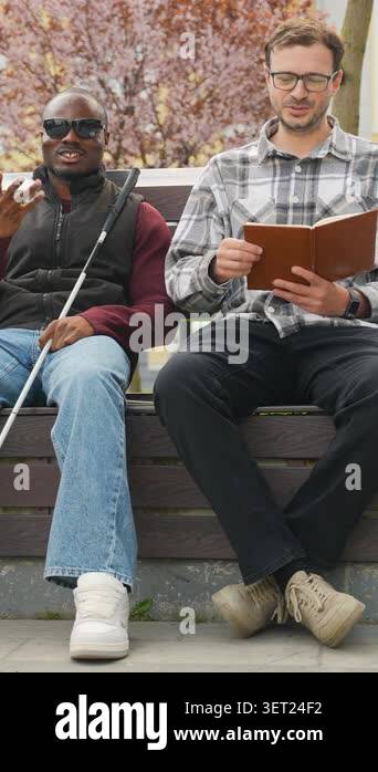 Volunteer reading a book aloud to an african american man with vision ...