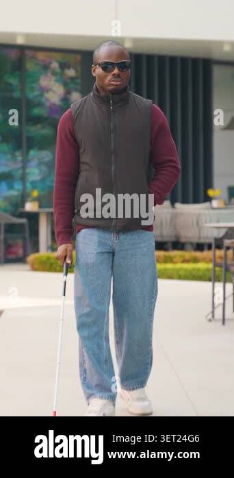 African american man with a visual impairment walking along a city ...