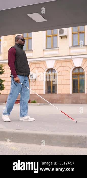 Independent man with visual impairment using a long cane for guidance ...