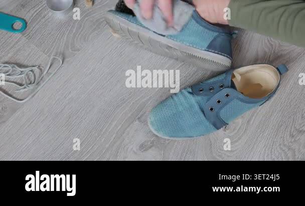 Cleaning process of blue suede sneakers with cloth on wooden floor ...
