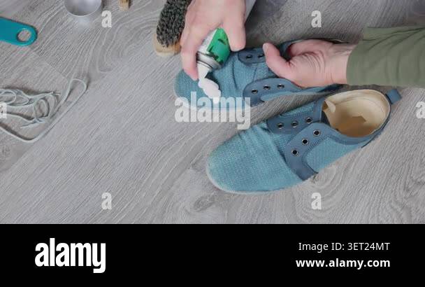 Person applying cleaning foam spray on blue textile shoes. Process of ...