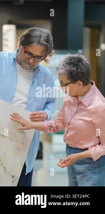 Elderly husband and wife choosing marble ceramic tiles for their home ...
