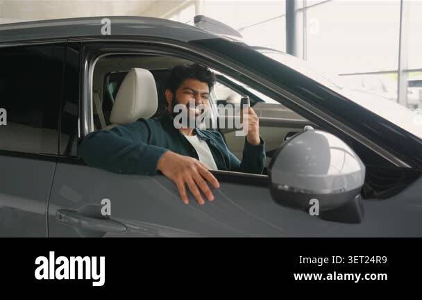 Happy indian man holding keys, sitting inside his new car at a ...