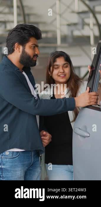 Joyful young indian couple examining a new car. The smiling man and ...