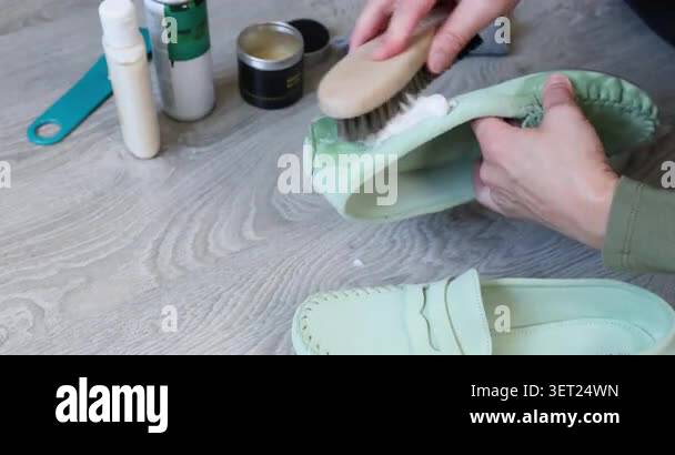 Woman hands brushing mint green suede loafer with active foam cleaner ...