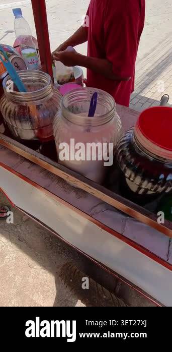 Vertical video of a street vendor preparing drinks from large jars ...