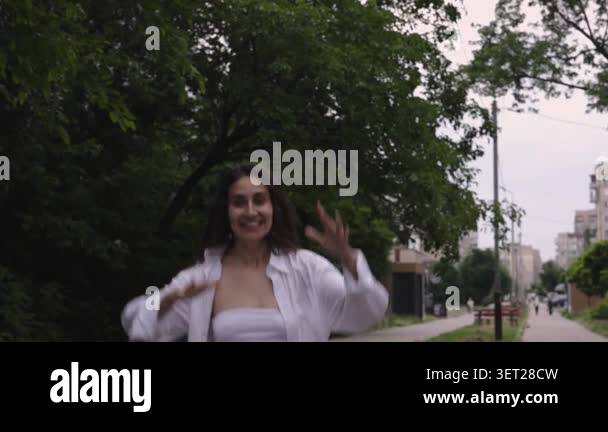 A cheerful young woman is walking in the park Stock Video Footage - Alamy