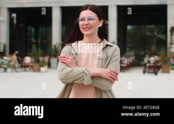 Young woman smiling with folded arms walking in city street in ...