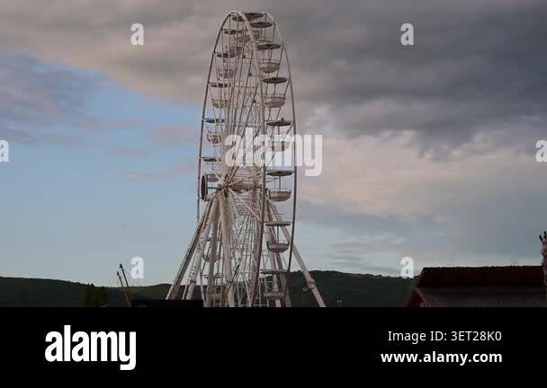 a wide shot of a large, white ferris wheel against a dramatic, cloudy ...