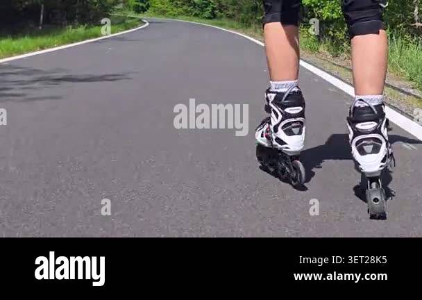 Young caucasian female using white inline skates in the park. Side view ...