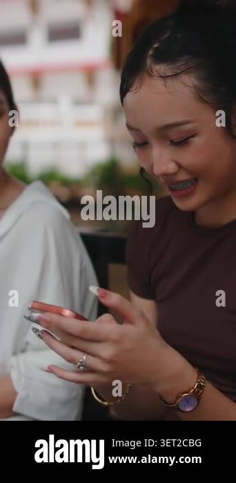 Two happy teenage girls smiling and sharing content on a mobile while ...