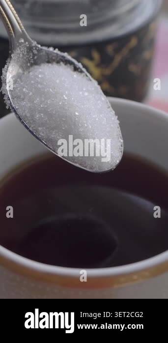 A person adds sugar to a cup of black tea in a cozy spot Stock Video ...