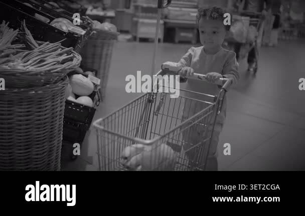 A toddler walks forward while pushing a small metal shopping cart past ...