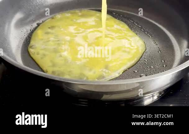 Egg mixture is poured into a frying pan, spreading and beginning to ...