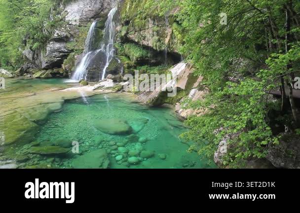 Beautiful waterfall cascading into clear turquoise water pool ...