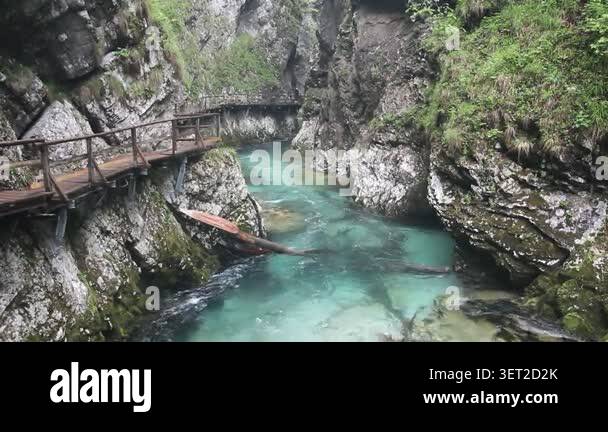 Wooden walkway along a turquoise river flowing through a narrow gorge ...