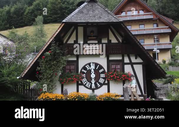 Large cuckoo clock building with a man figure and flowers in front ...