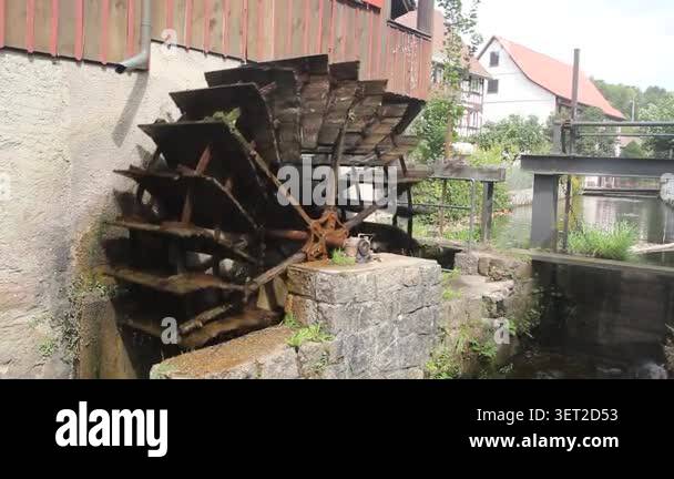 Old wooden water wheel turning slowly in a stream, powering an old mill ...