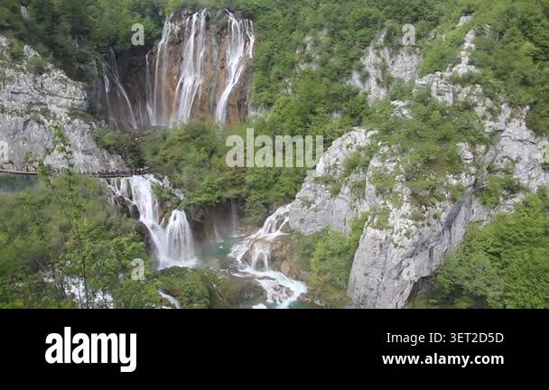 Wide shot of cascading waterfalls flowing down rocky cliffs surrounded ...
