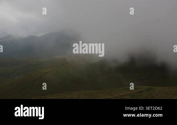 Misty clouds drift over green mountain slopes in this atmospheric ...