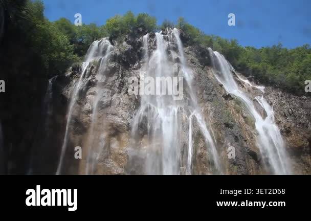Wide shot of a large waterfall cascading down a rocky cliff face ...