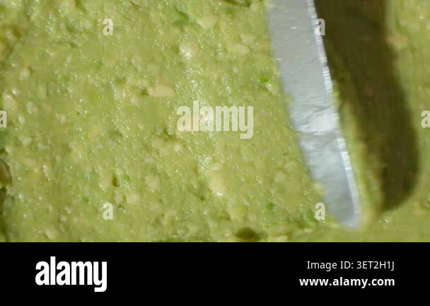 Macro shot of homemade mashed avocado puree being smoothed with a knife ...