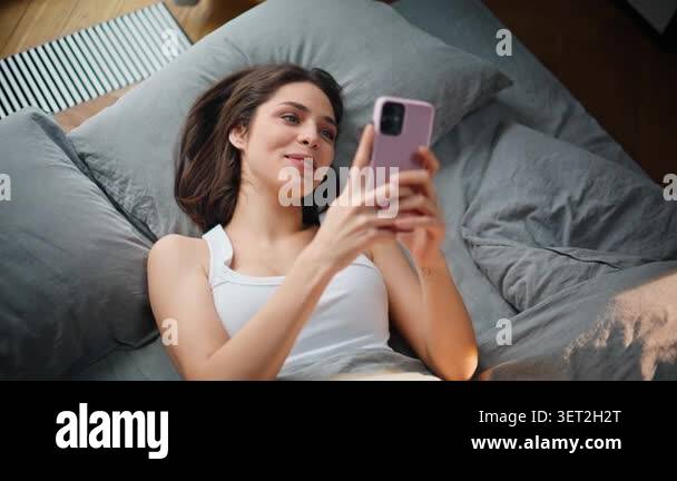 Closeup lying woman messaging mobile phone resting bed early morning ...